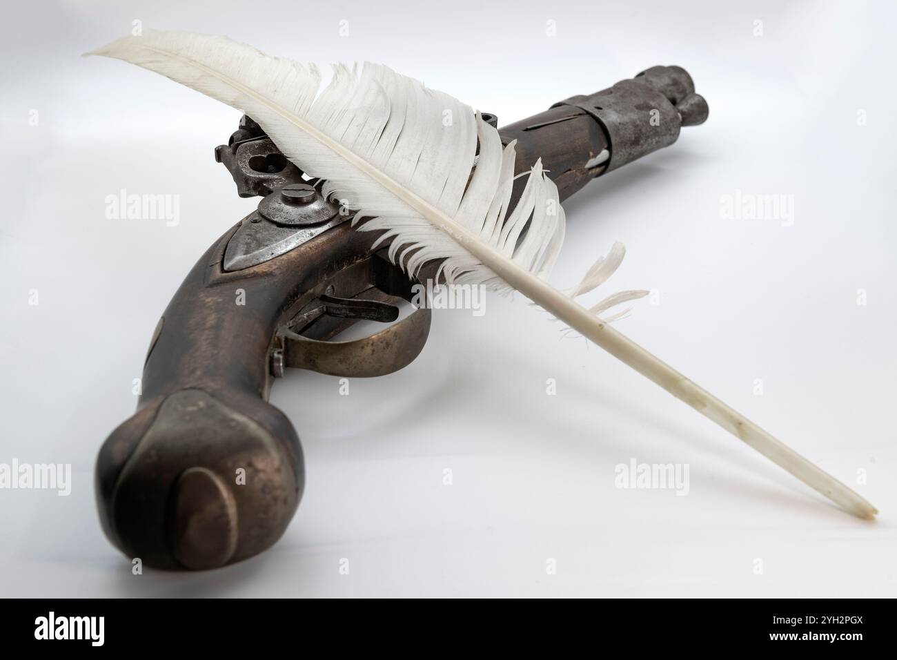 Goose feather and antique pistol on white background Stock Photo - Alamy