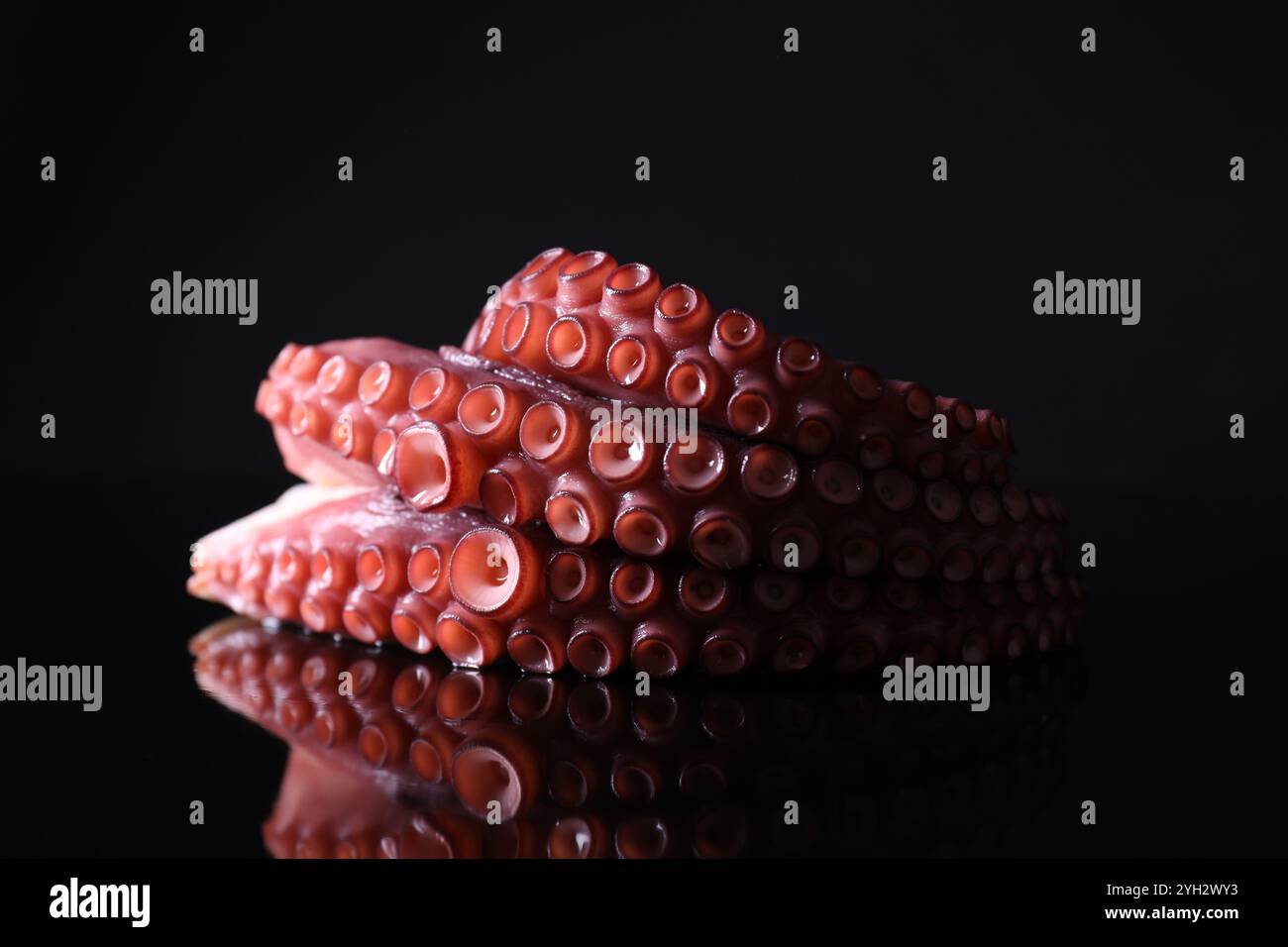 Cut fresh raw octopus on black mirror surface Stock Photo - Alamy