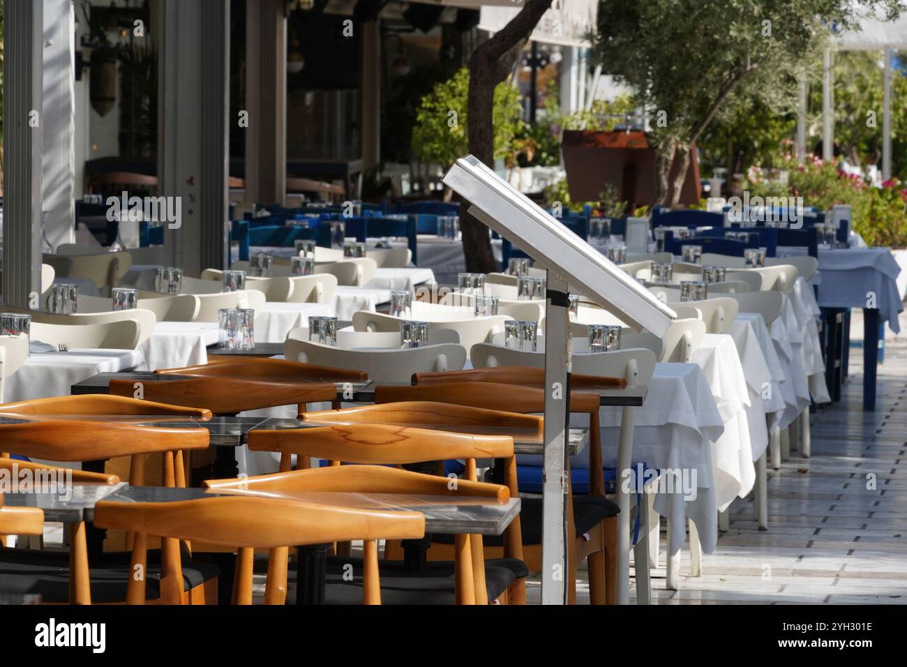 An empty outdoor restaurant with a menu stand prominently displayed for ...