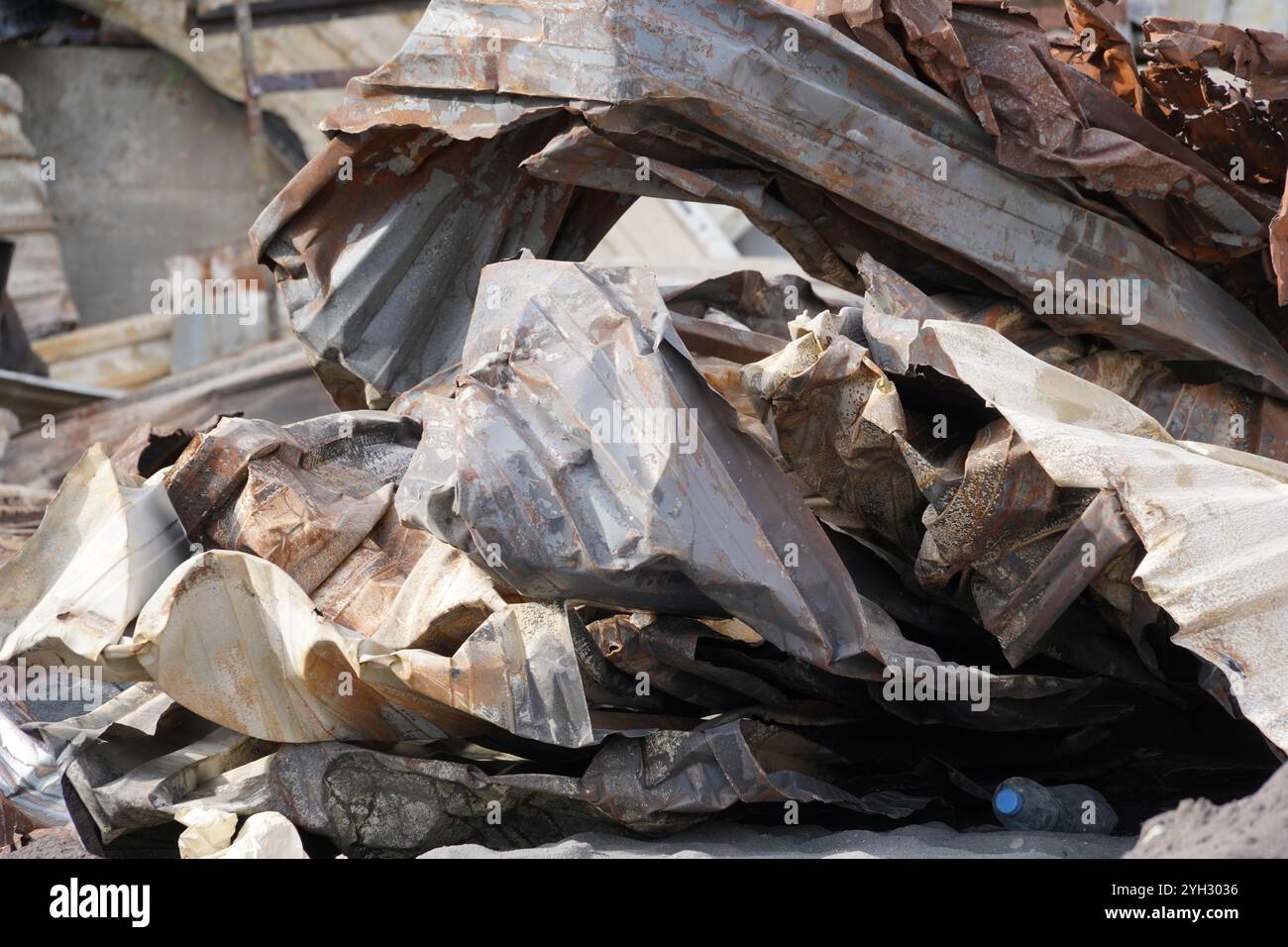 Corrugated aluminium sheets, warped and blackened by fire, are now only ...