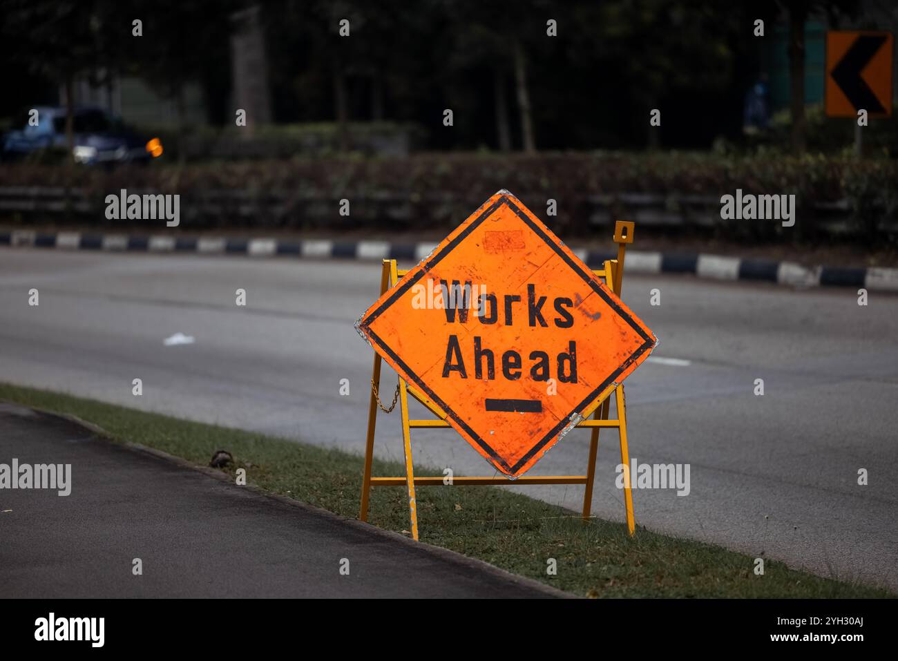 Orange road sign roadworks ahead, standing in the middle of the road ...