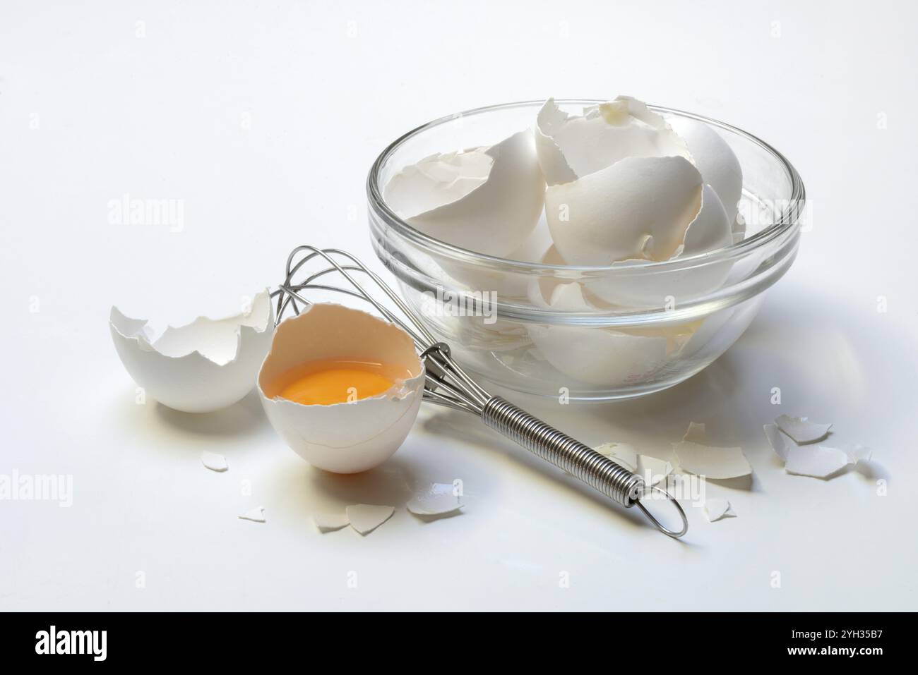 Egg shells in a glass bowl, whisk and opened hen's egg Stock Photo - Alamy