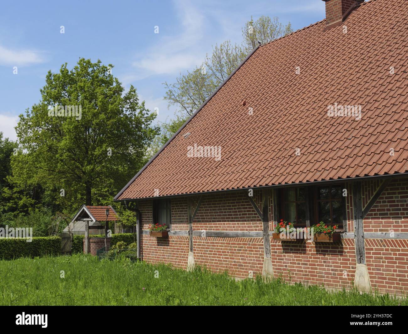 Brick barn with red roof surrounded by green nature and flowers ...
