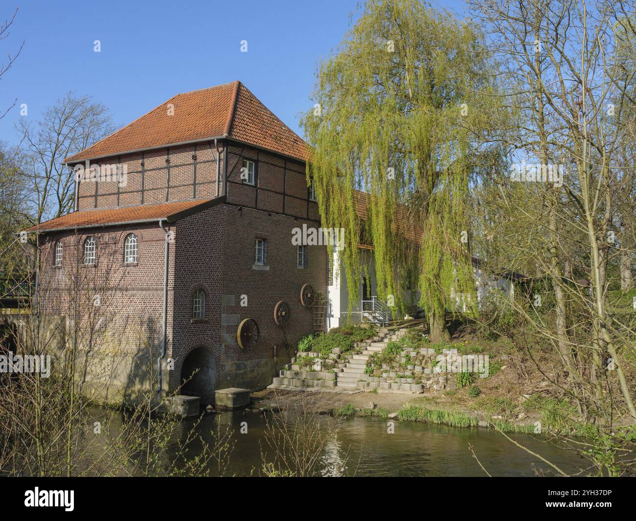 Historic brick mill on a small river surrounded by green trees, metelen ...