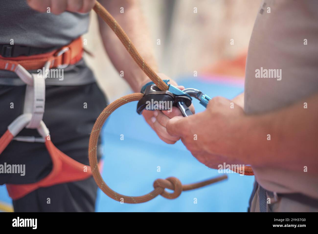 Rock wall climber wearing safety harness and climbing equipment indoor ...