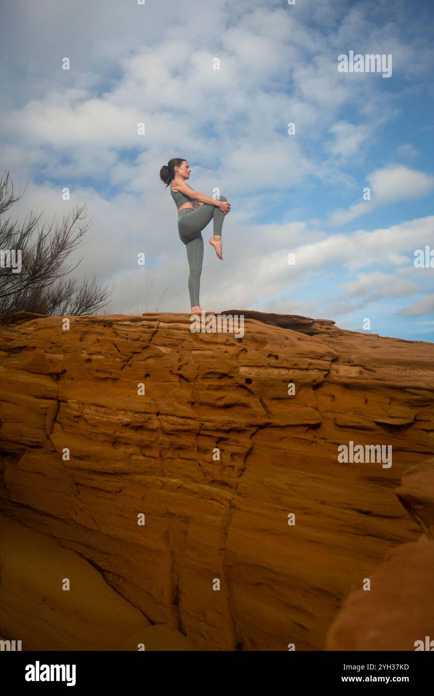 fit sporty woman standing on top of rock in desert doing a leg ...