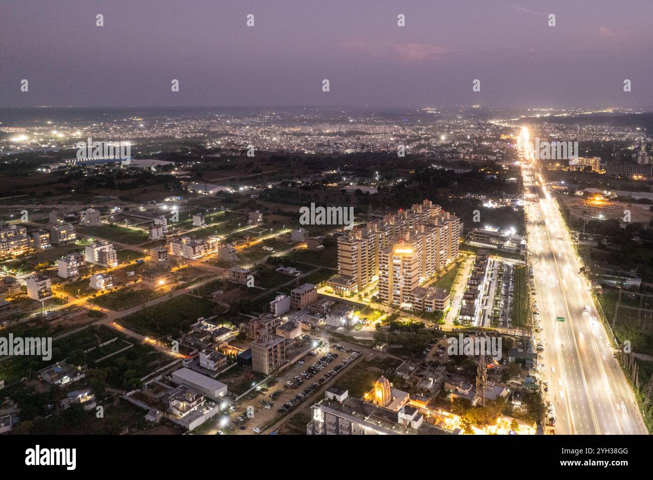 aerial drone dusk dawn shot showing busy lit highway and skyscrapers ...