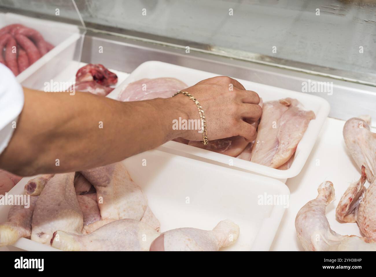 Butcher serving fresh chicken meat at display in butchery Stock Photo ...