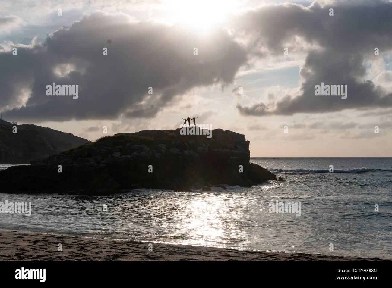Silhouettes of human figures backlit on a sunset on a beach in the ...