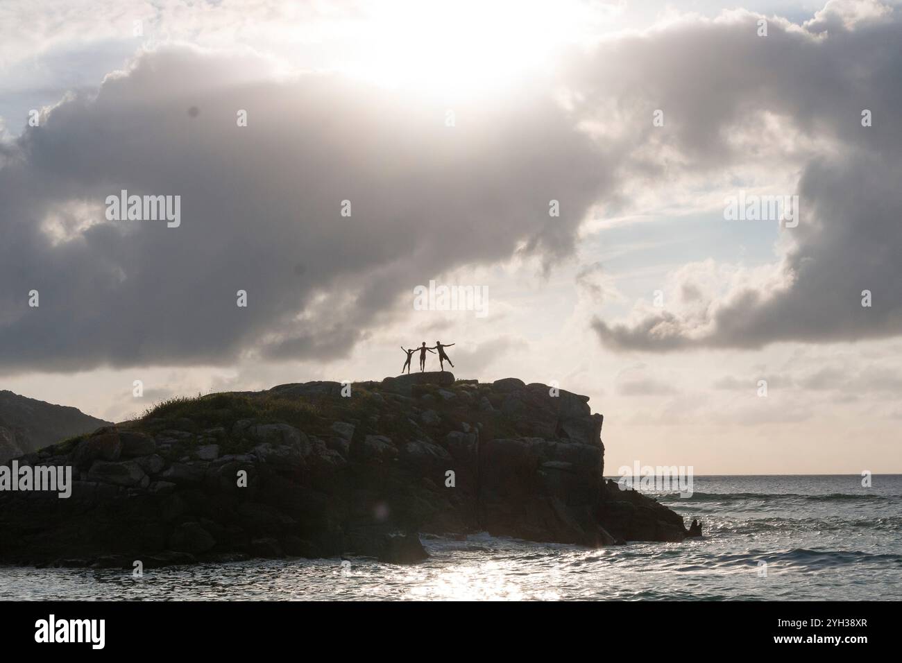 Silhouettes of human figures backlit on a sunset on a beach in the ...
