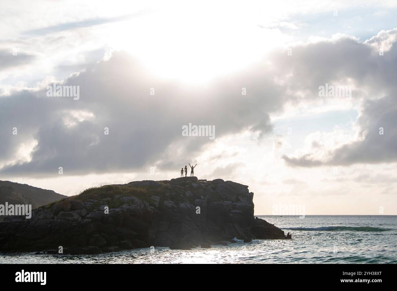 Silhouettes of human figures backlit on a sunset on a beach in the ...
