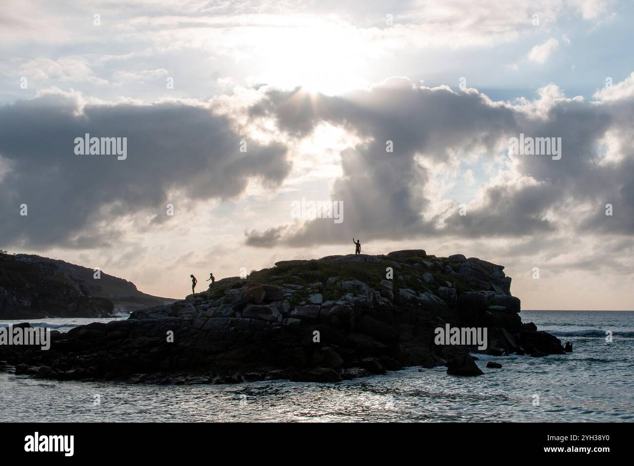 Silhouettes of human figures backlit on a sunset on a beach in the ...