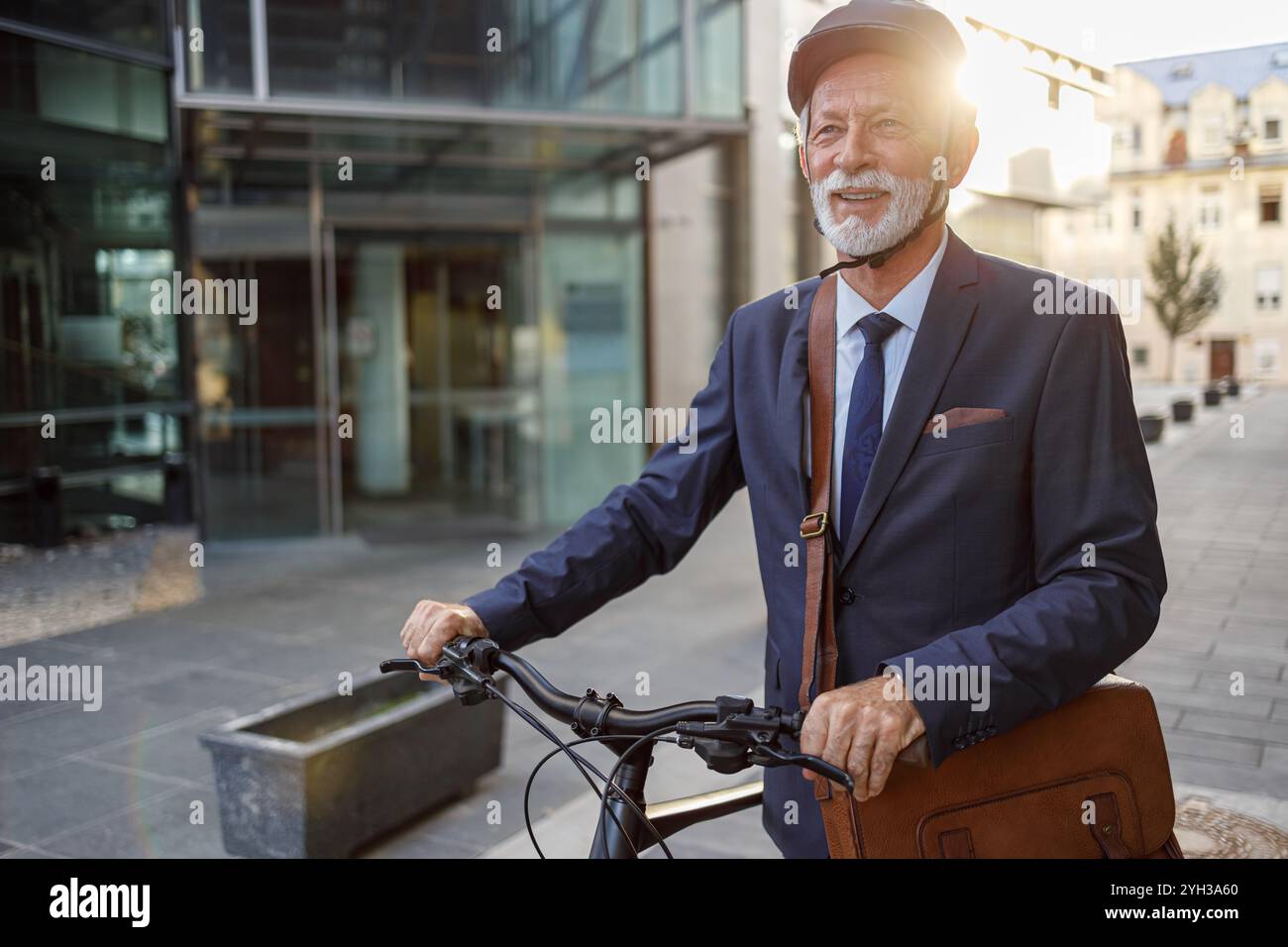 Portrait of smiling senior manager with helmet and bag pushing his ...