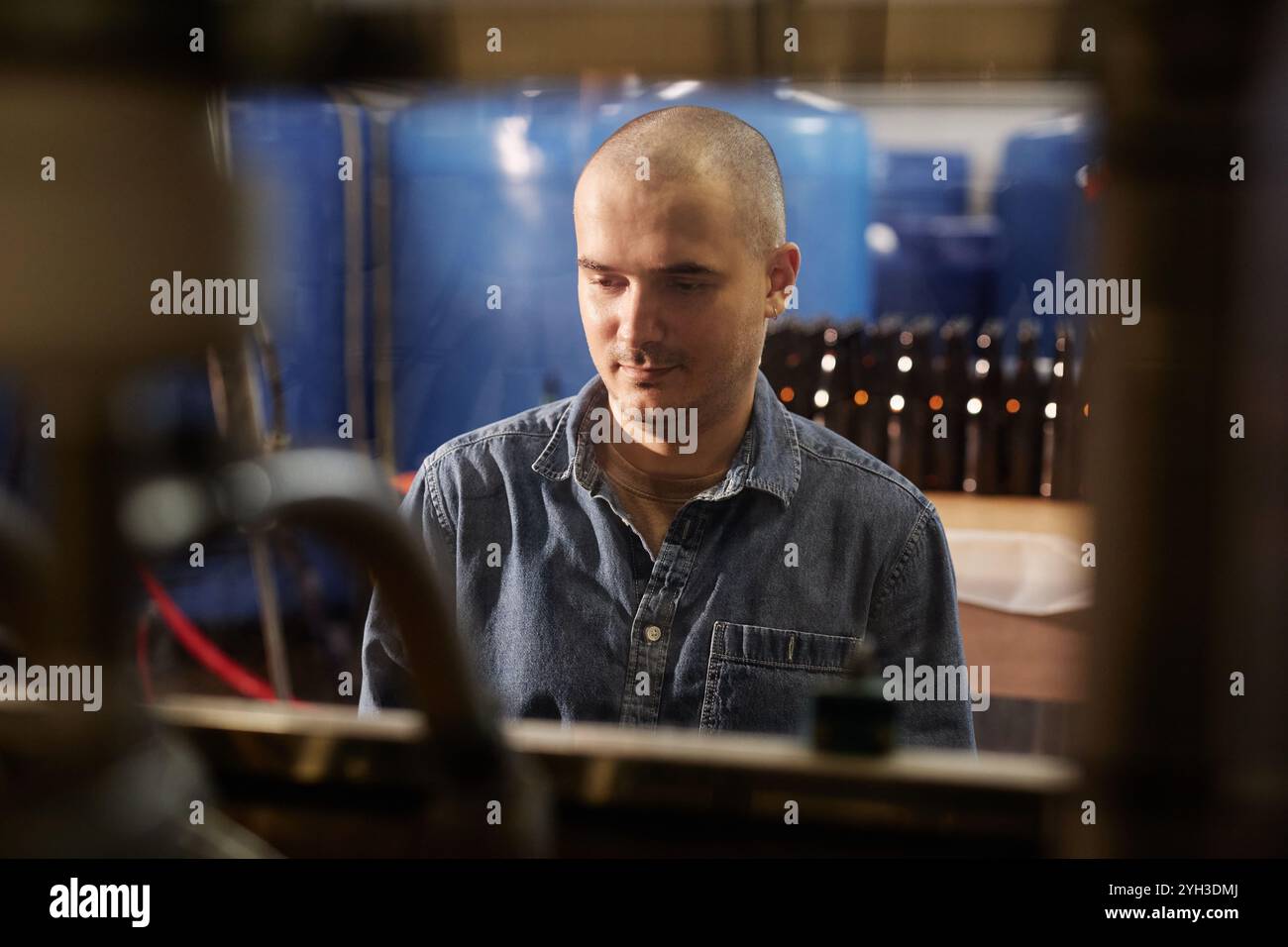 Shot through factory machinery of happy male production worker wearing ...