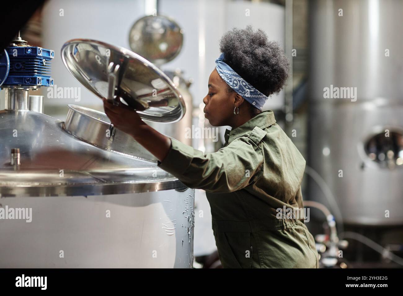 Side view of female African American process supervisor opening lid of ...