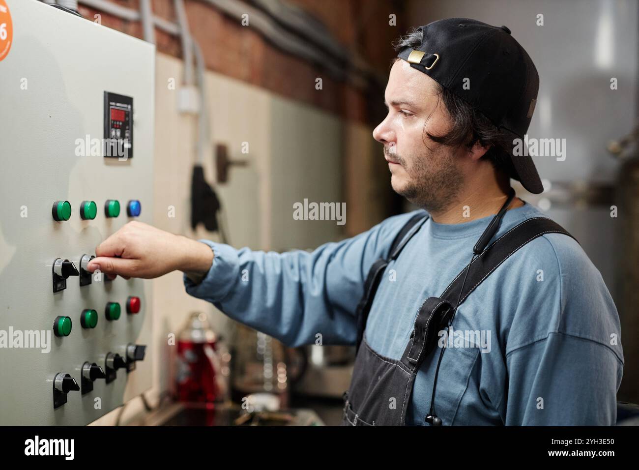 Side view of concentrated male production worker operating factory ...