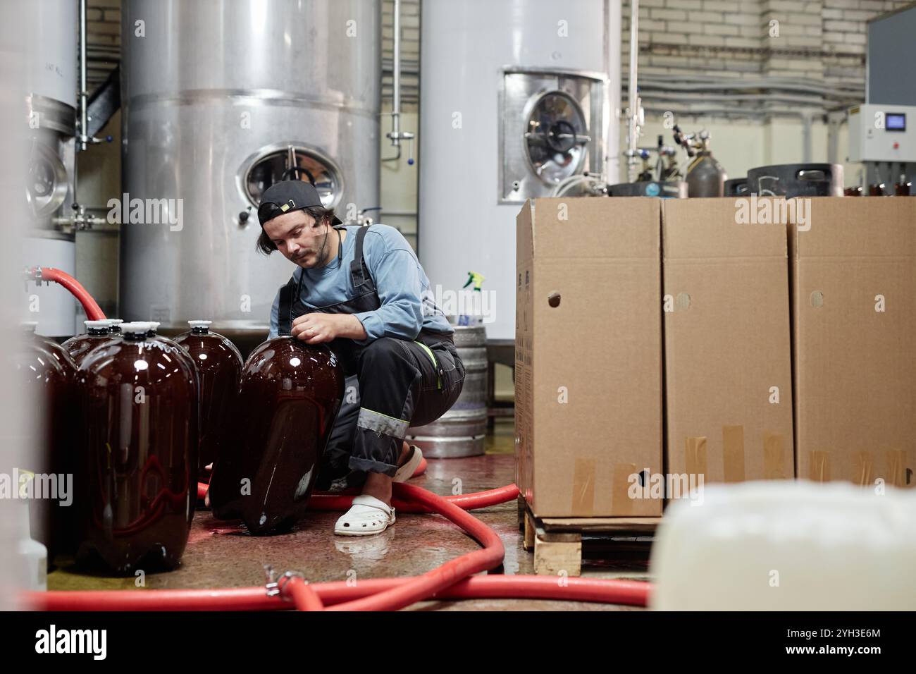 Hard working male production operator lifting huge keg of craft cider ...