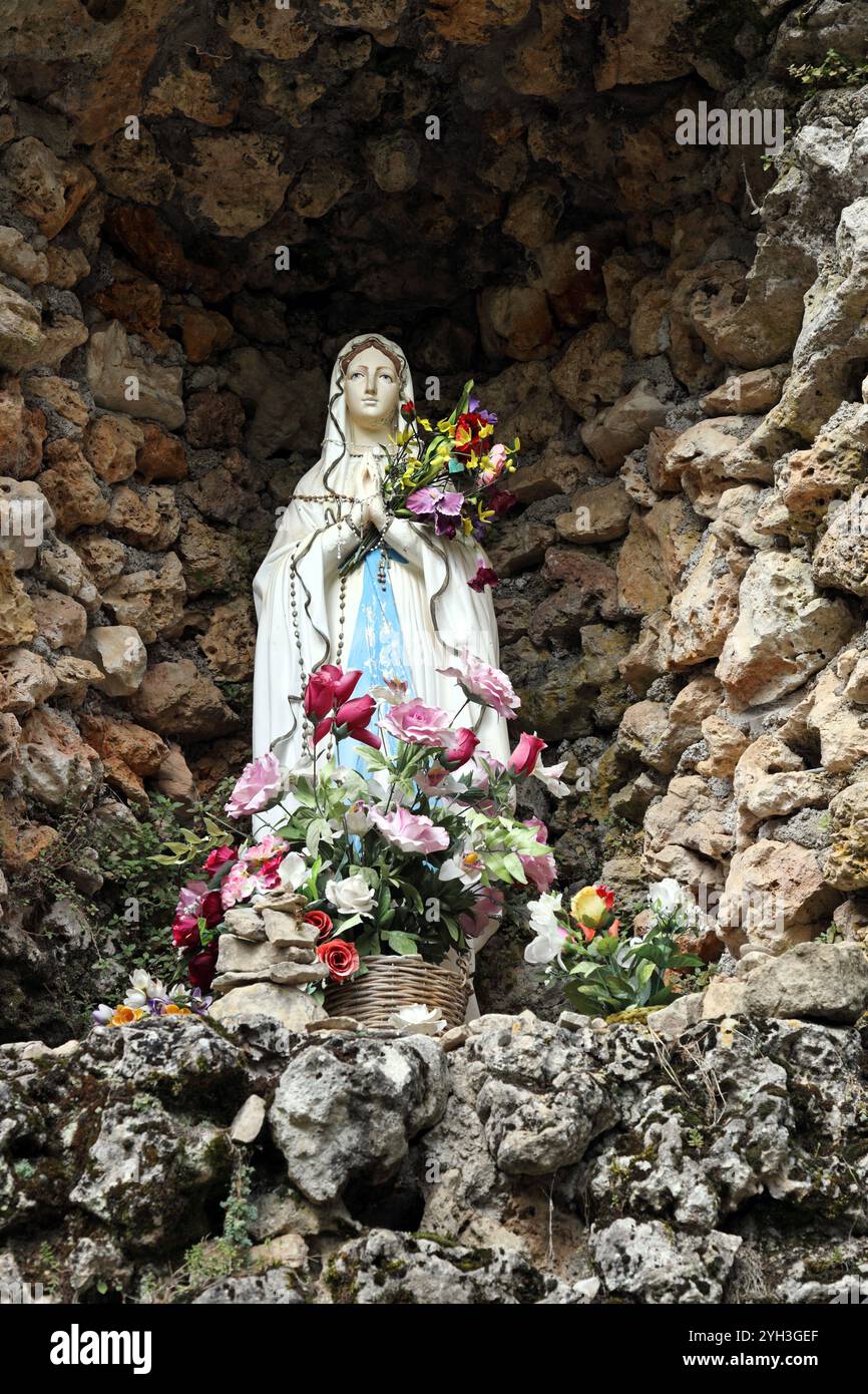 Trailside Madonna statue with floral offerings on a hiking trail near ...