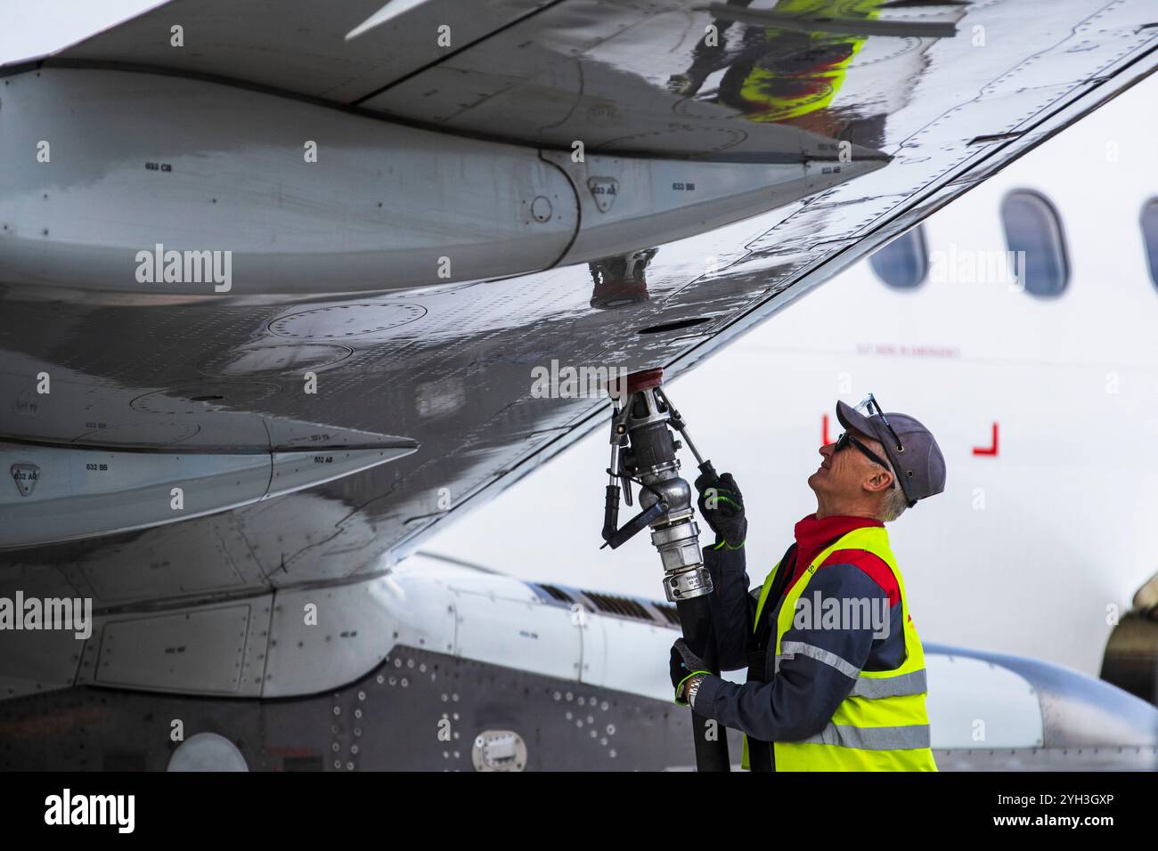Ground crew member fueling an aircraft with a refueling hose at an ...