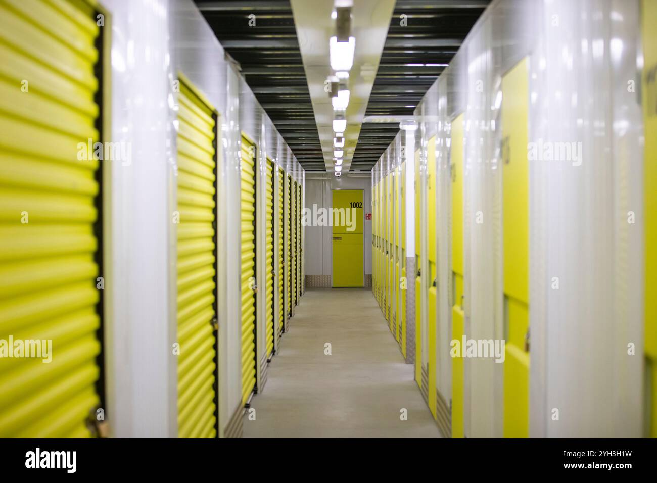 Bright storage facility hallway with yellow roll-up doors and ...