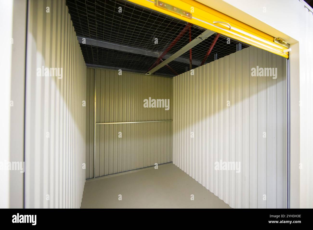 Empty storage unit with yellow roll-up door and secure metal walls in a ...