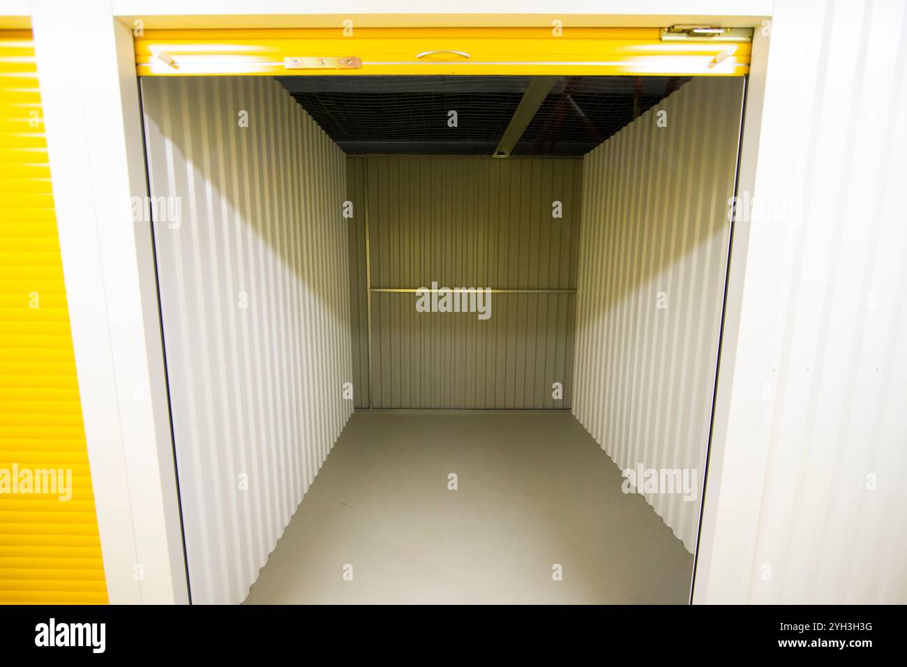 Empty storage unit with yellow roll-up door and secure metal walls in a ...