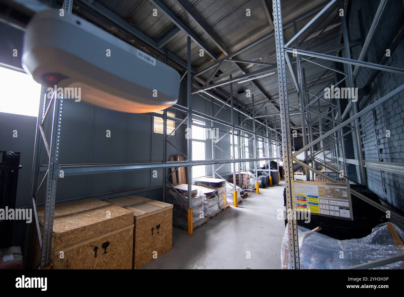 Warehouse interior with steel shelving, packed pallets, and crates in a ...