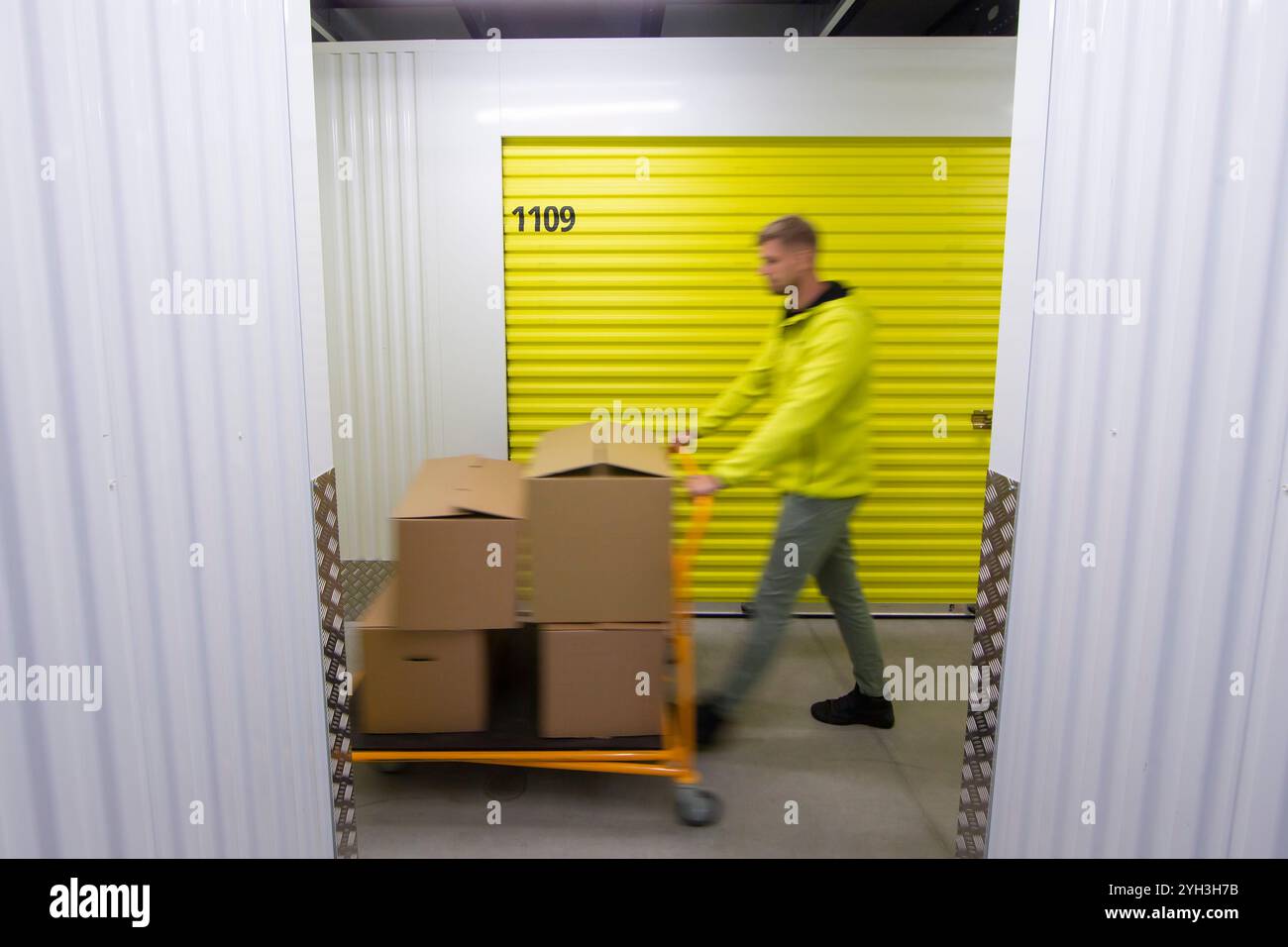 Man pushing a cart with boxes in a storage facility hallway with a ...