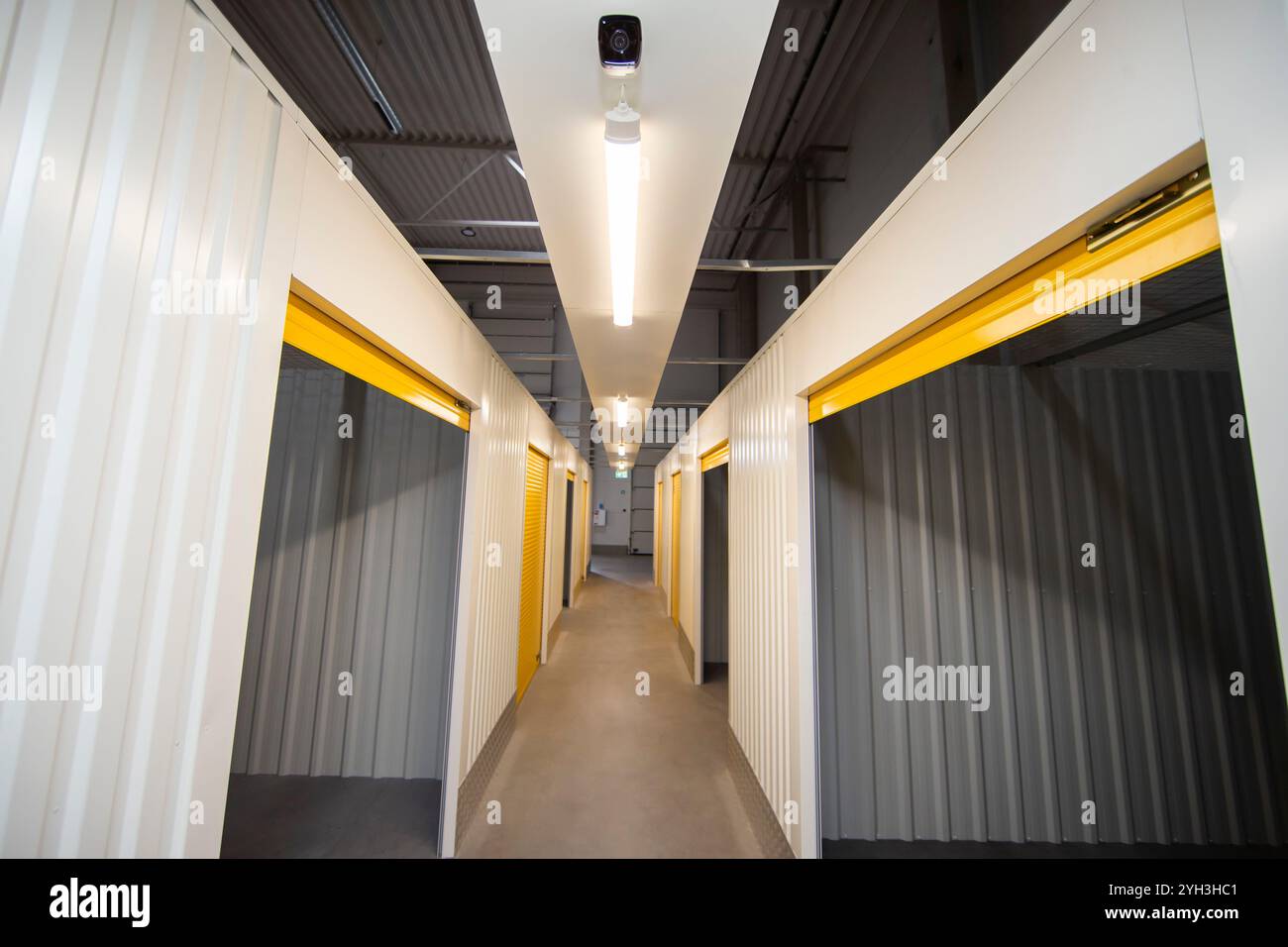 Storage facility corridor with open yellow storage units and overhead ...