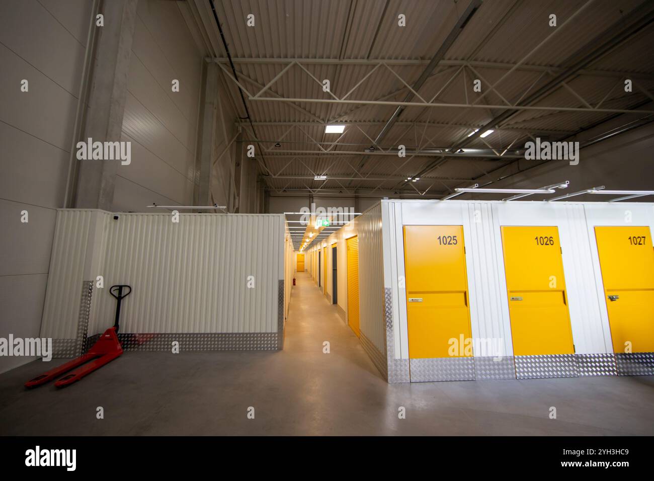 Storage facility with numbered yellow doors, a long corridor, and a red ...