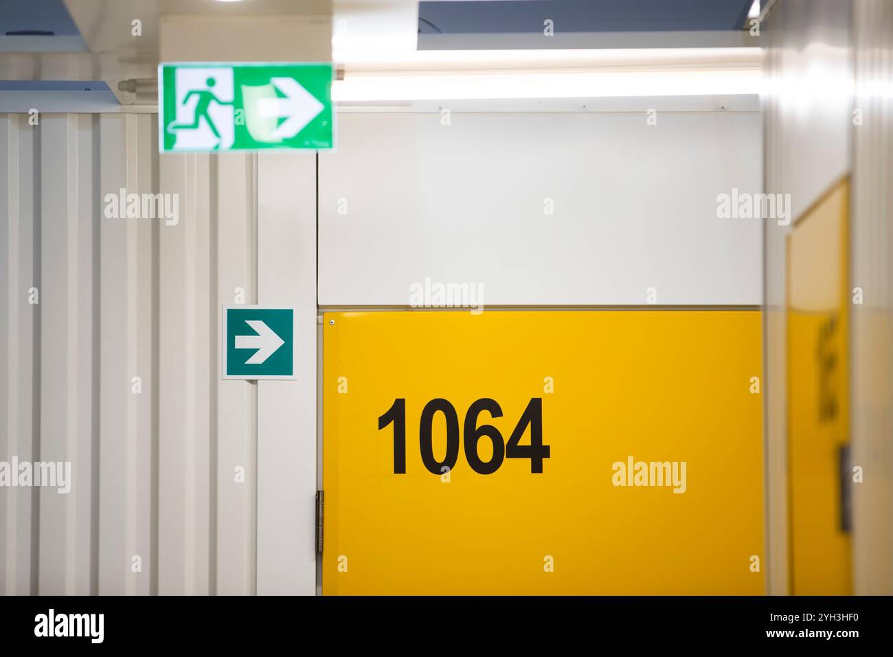 Yellow storage unit door numbered 1064 with overhead emergency exit ...