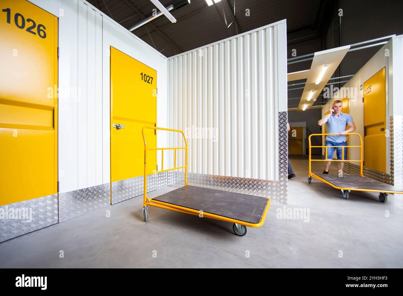 Storage facility with yellow doors, orange carts, and a man in the ...