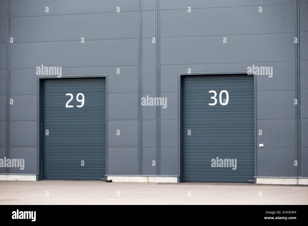 Exterior view of two numbered industrial storage doors on a gray wall ...