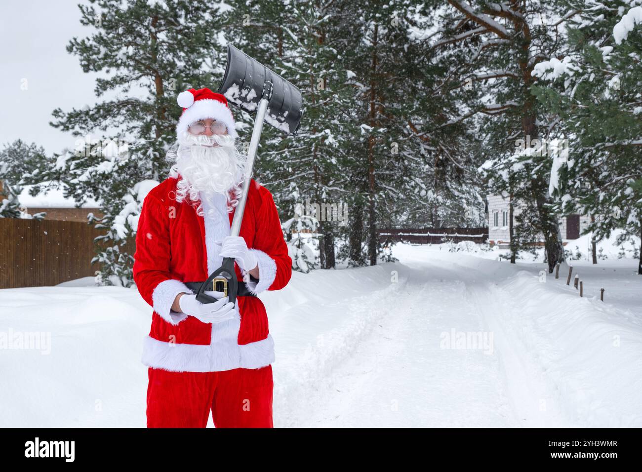 Santa Claus cleans snow with shovel in winter outdoors after a snowfall ...