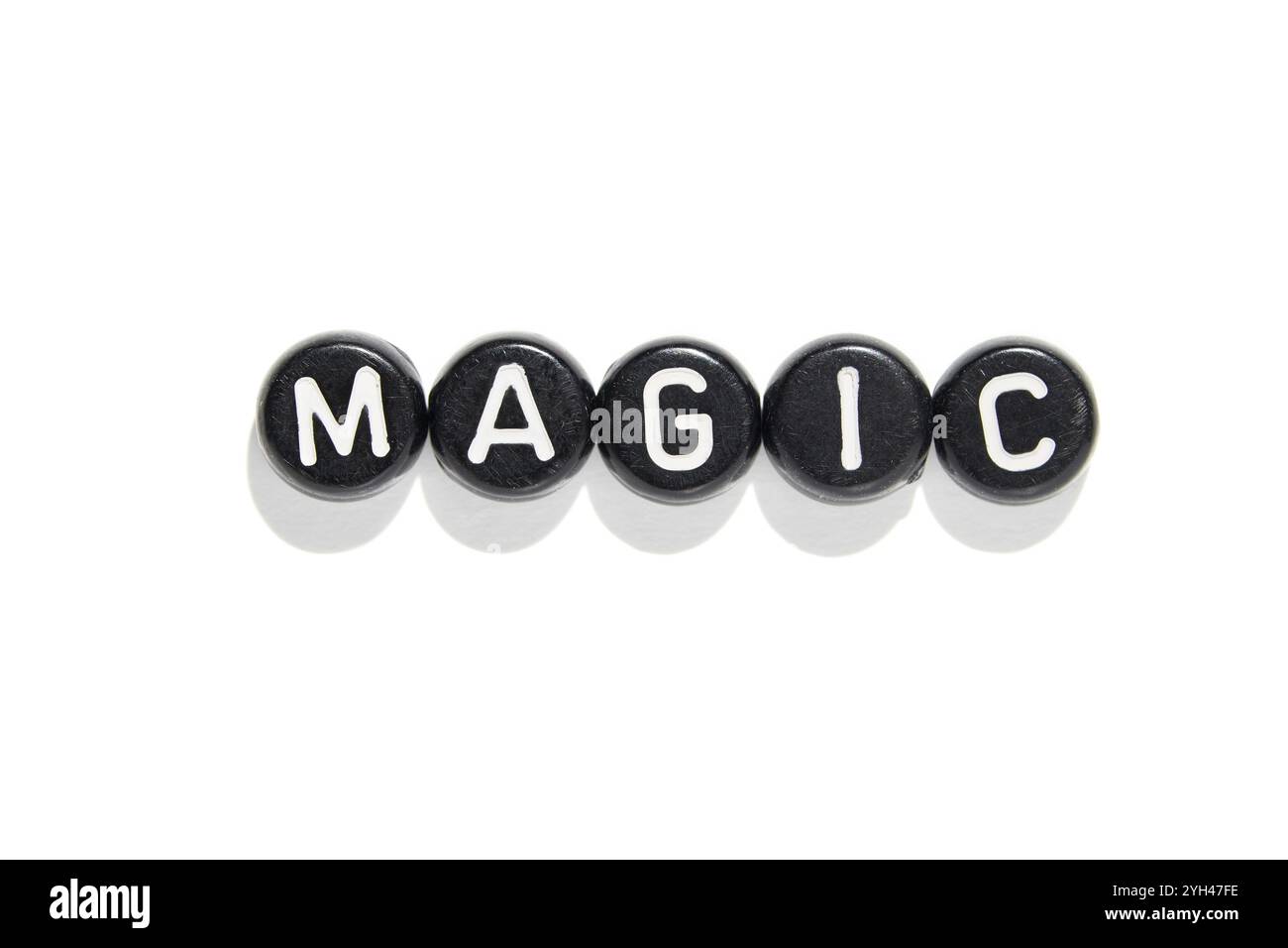 Black beads with white letters spelling magic on white background for ...
