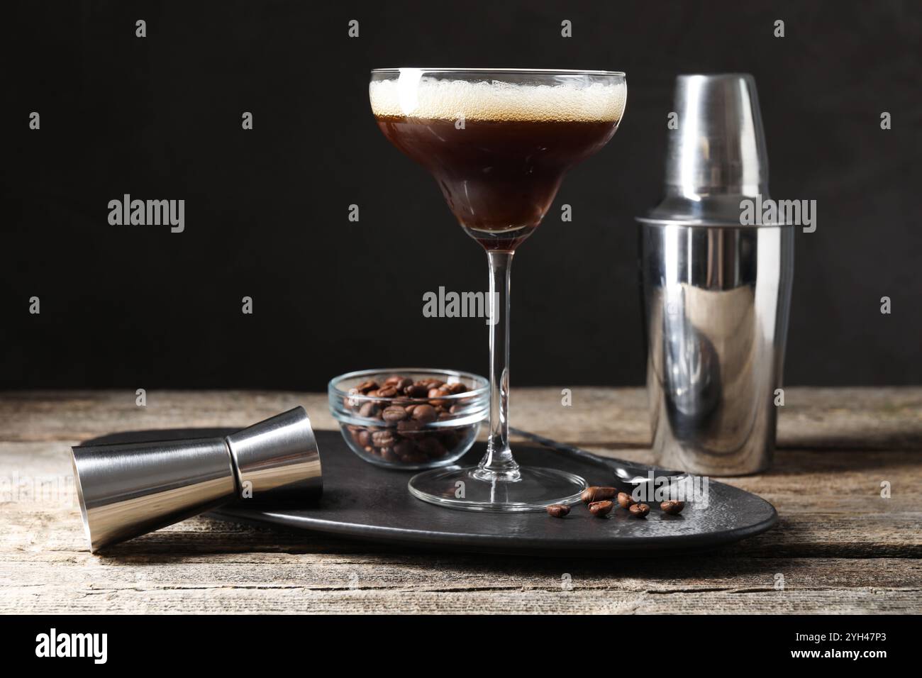Glass of delicious espresso martini, jigger, shaker and coffee beans on ...