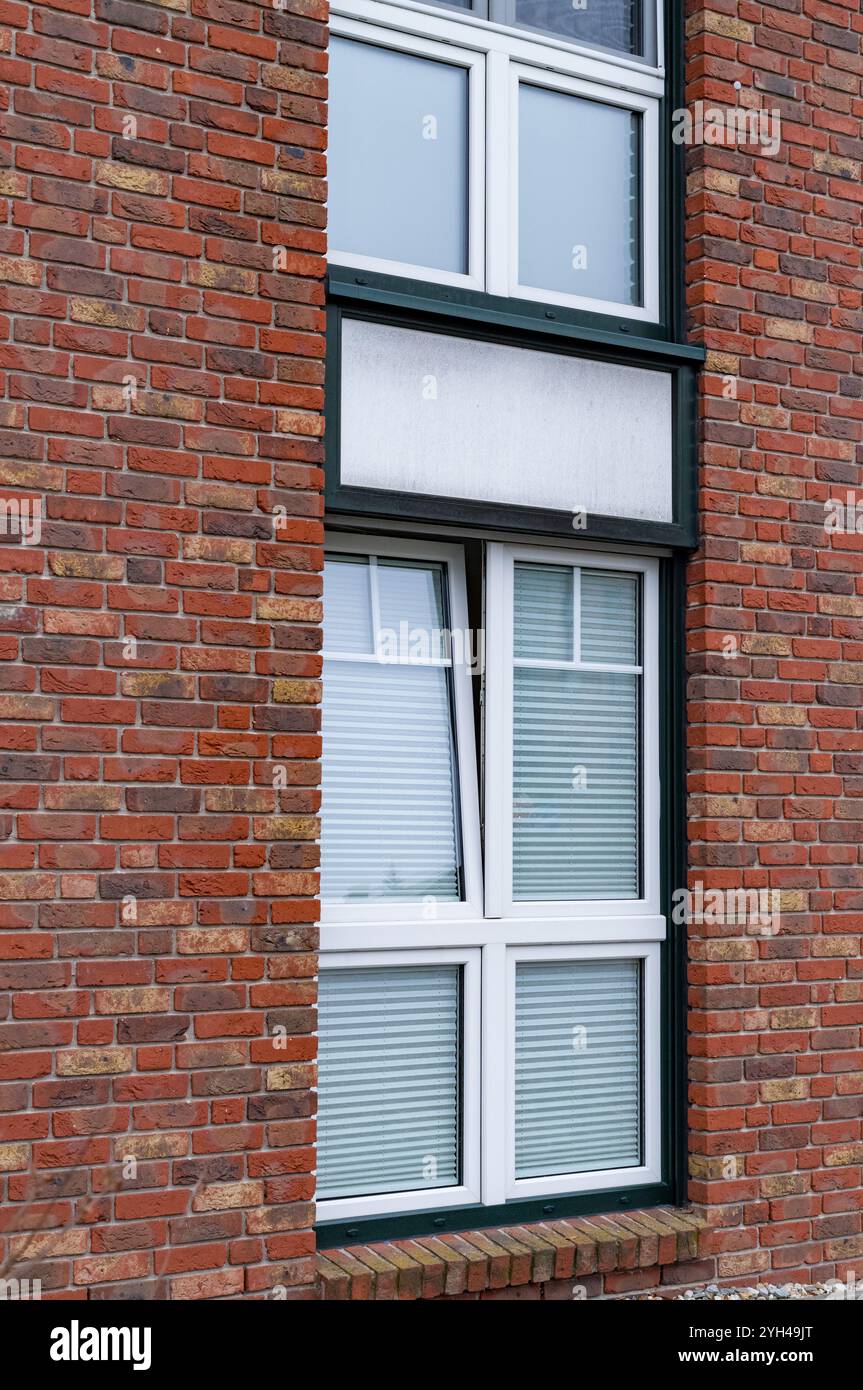 Opened window with lowered venetian blinds on red brick wall allowing ...