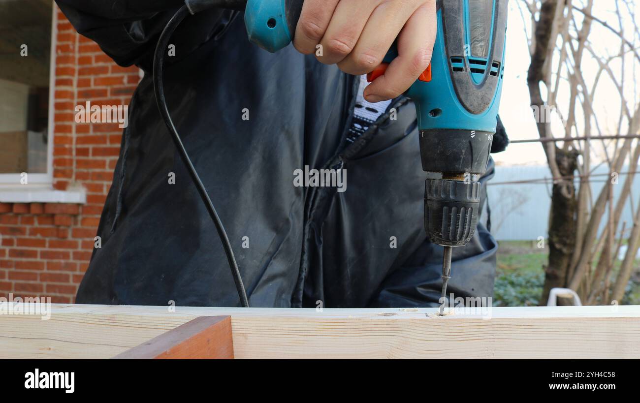 worker in warm work clothes with electric screwdriver screws screws ...