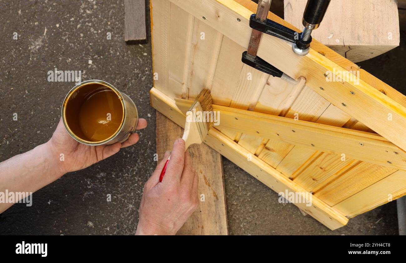 painting or varnishing a homemade small door made of light planks using ...