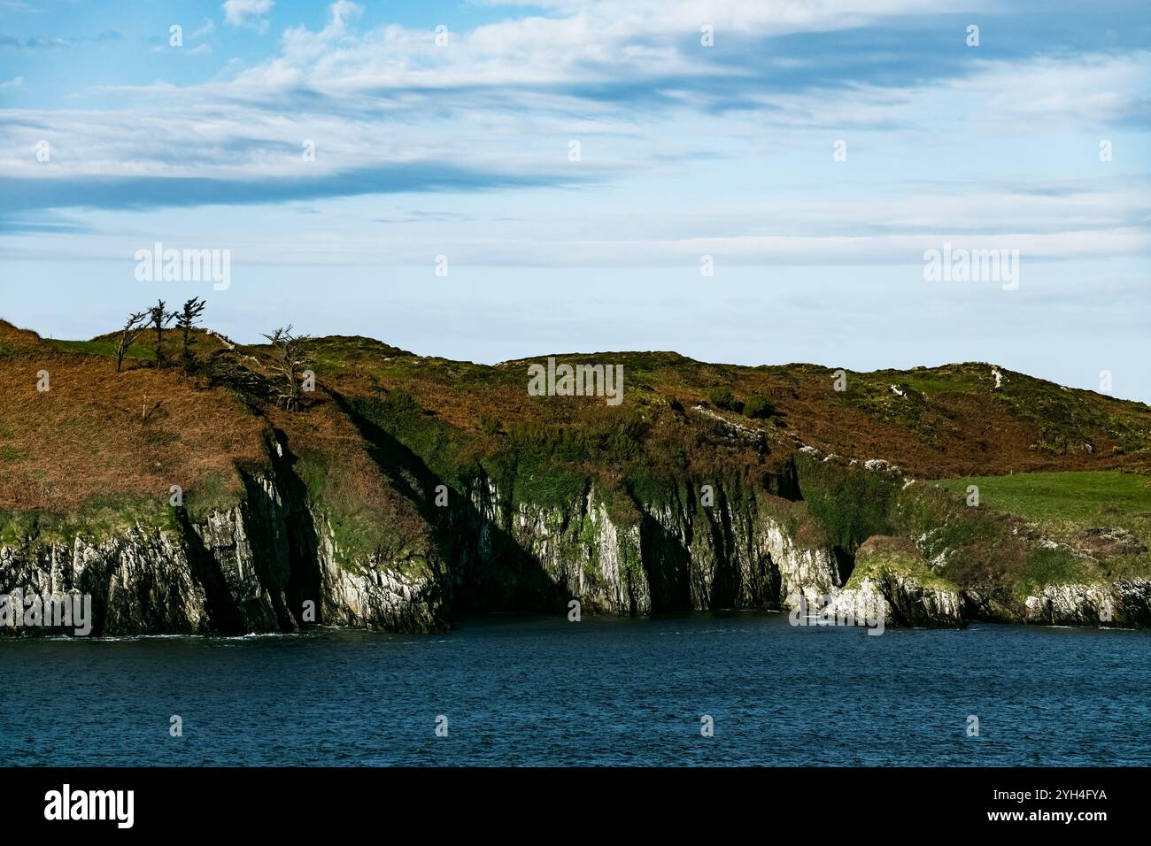 Coastal cliff landscape with rugged rocks and trees near the water ...
