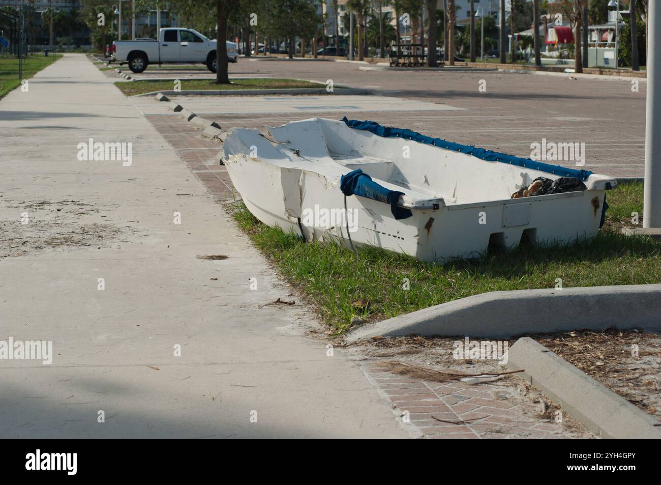 Leading lines view down the sidewalk with a small white row boat. Green ...