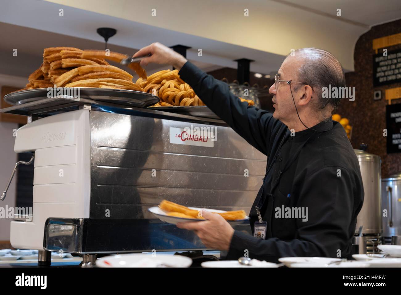 A waiter seves traditional churros and porras at Cafeteria Esparteros ...