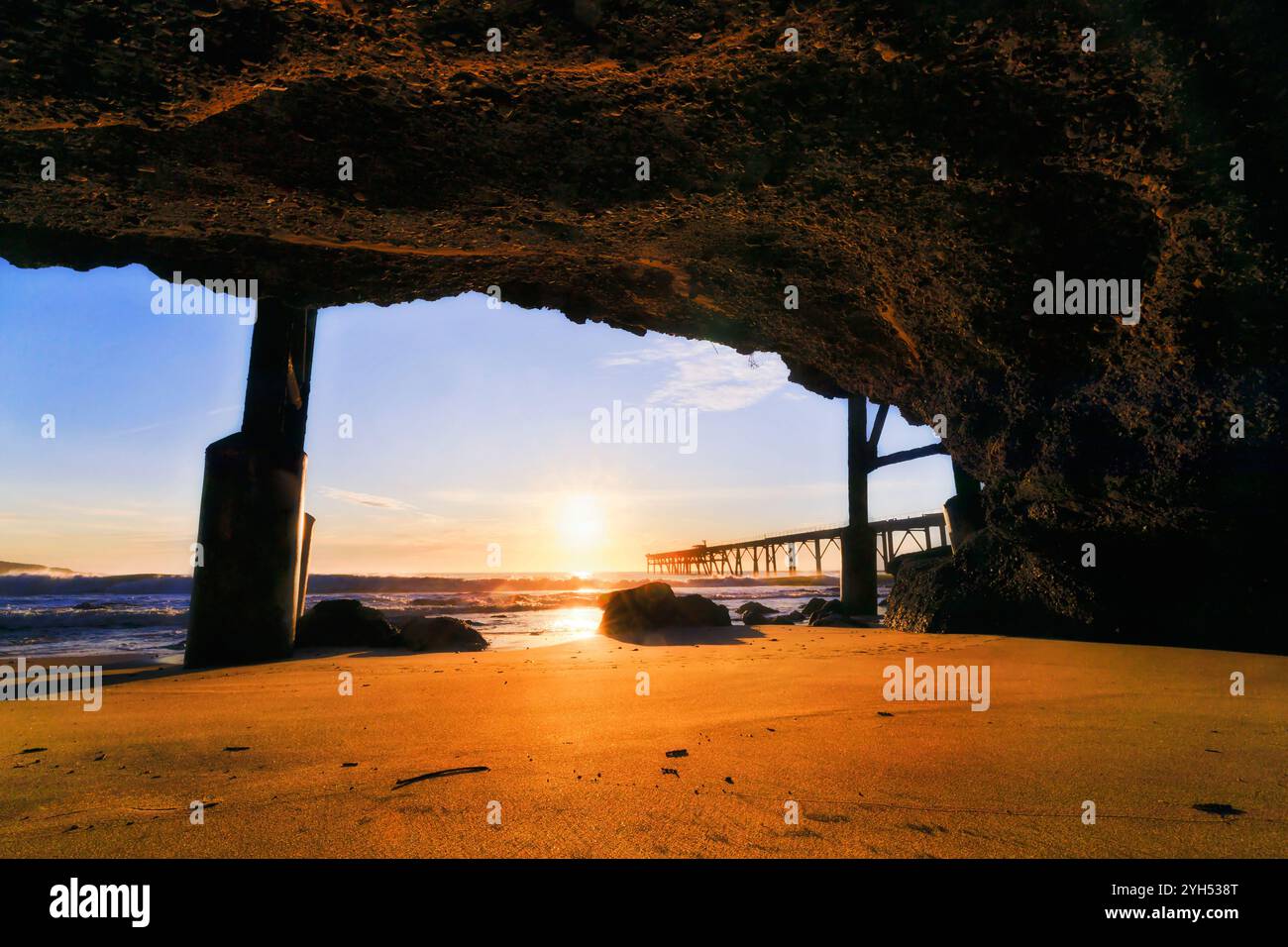 Rising sun light from inside sandstone cave on Middle Camp beach of ...