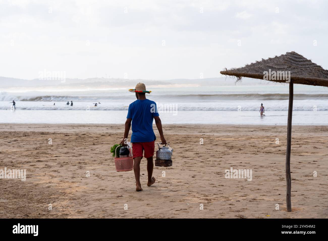 Back view a man carrying a hot teapot and busket with fresh mint ...