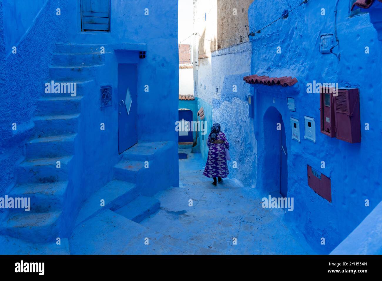 An unrecognizable woman in traditional dress walking away at a blue ...