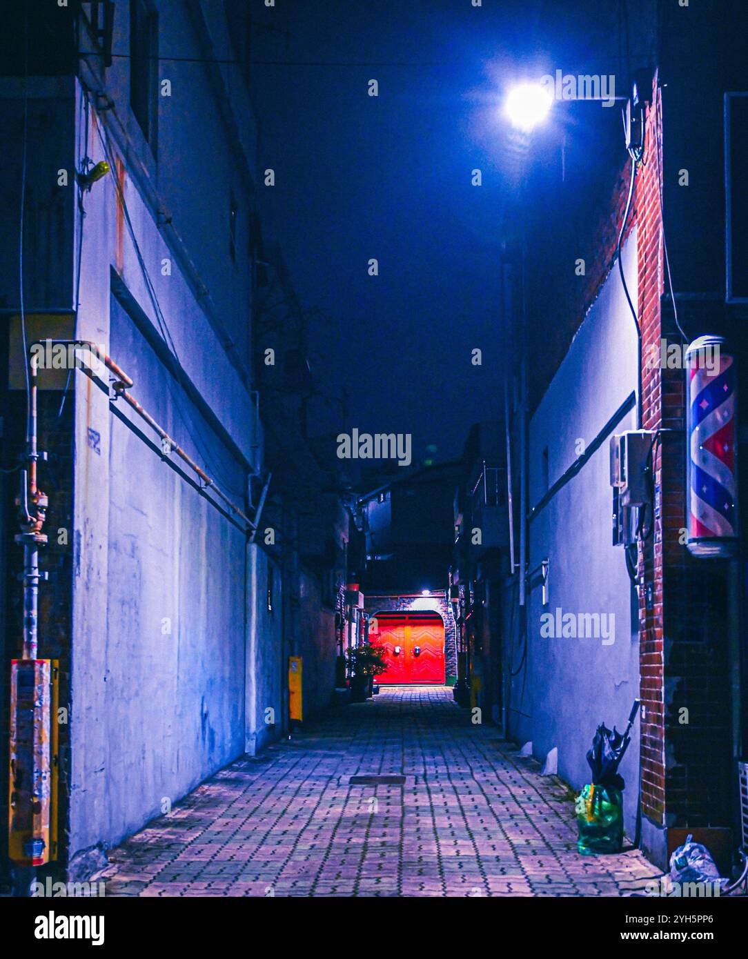 Quiet Alleyway with Barber Pole and Red Door at Night Stock Photo - Alamy