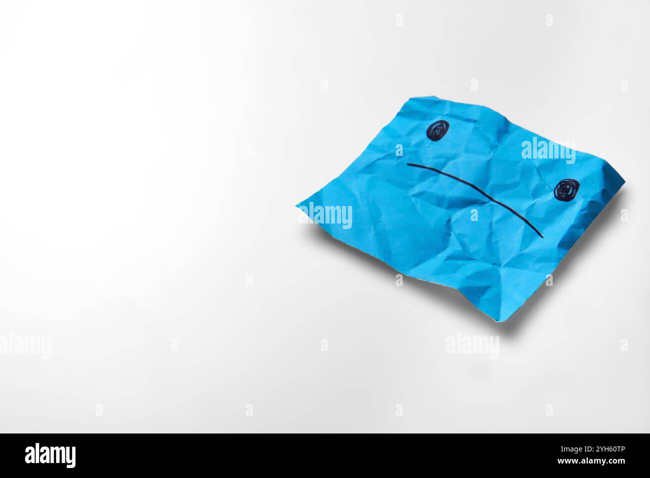 Sad light blue paper face on a white background. Blue Monday concept ...