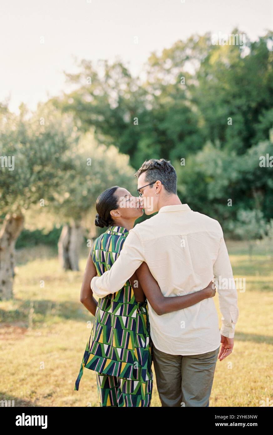 Man kisses woman while standing and hugging in a green garden. Back ...