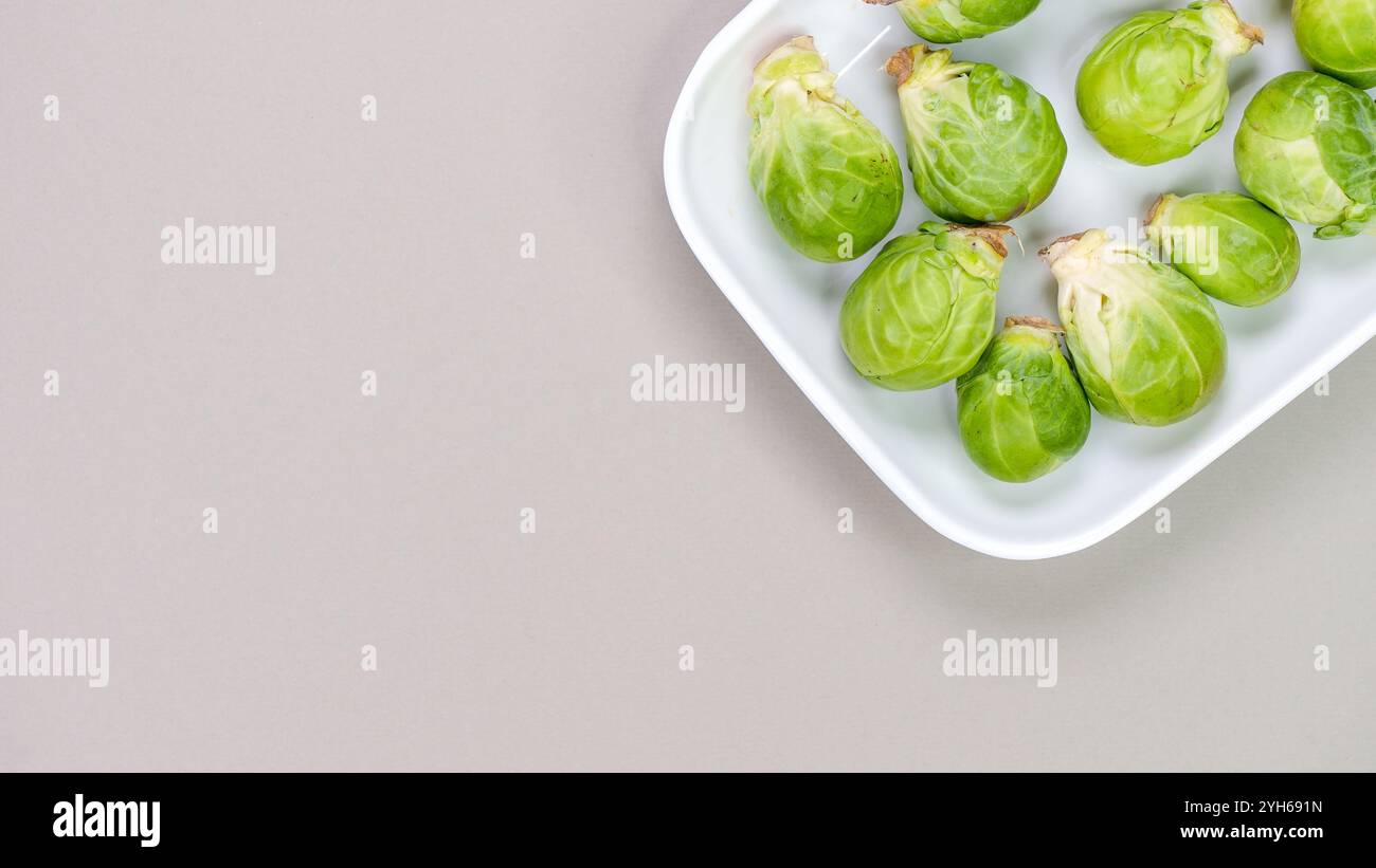 Fresh green brussels sprouts in a white container on a gray background ...