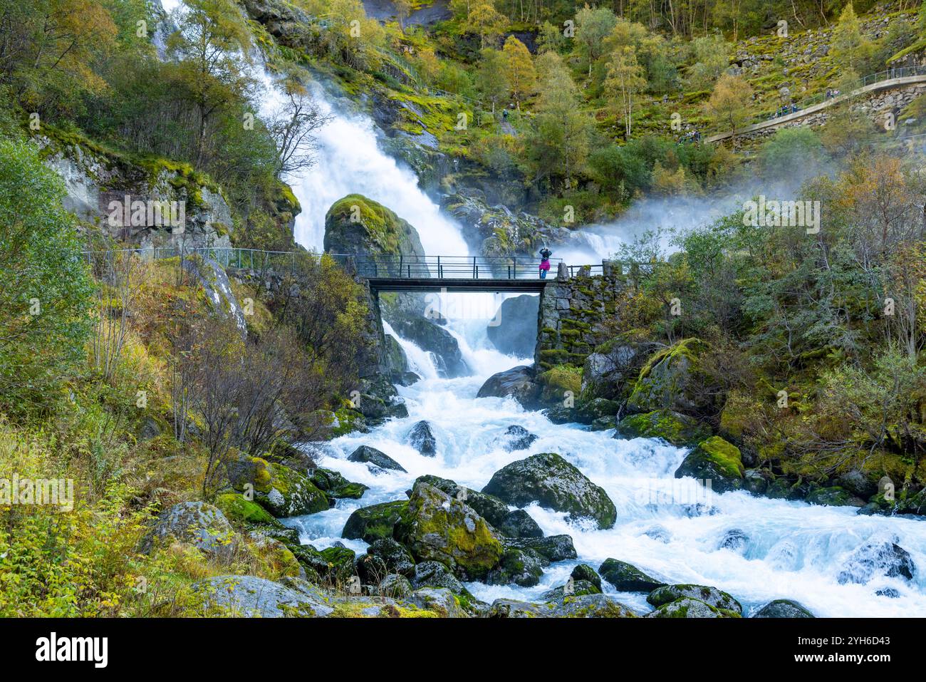 Woman takes a photograph of the famous Kleivafossen waterfall in ...